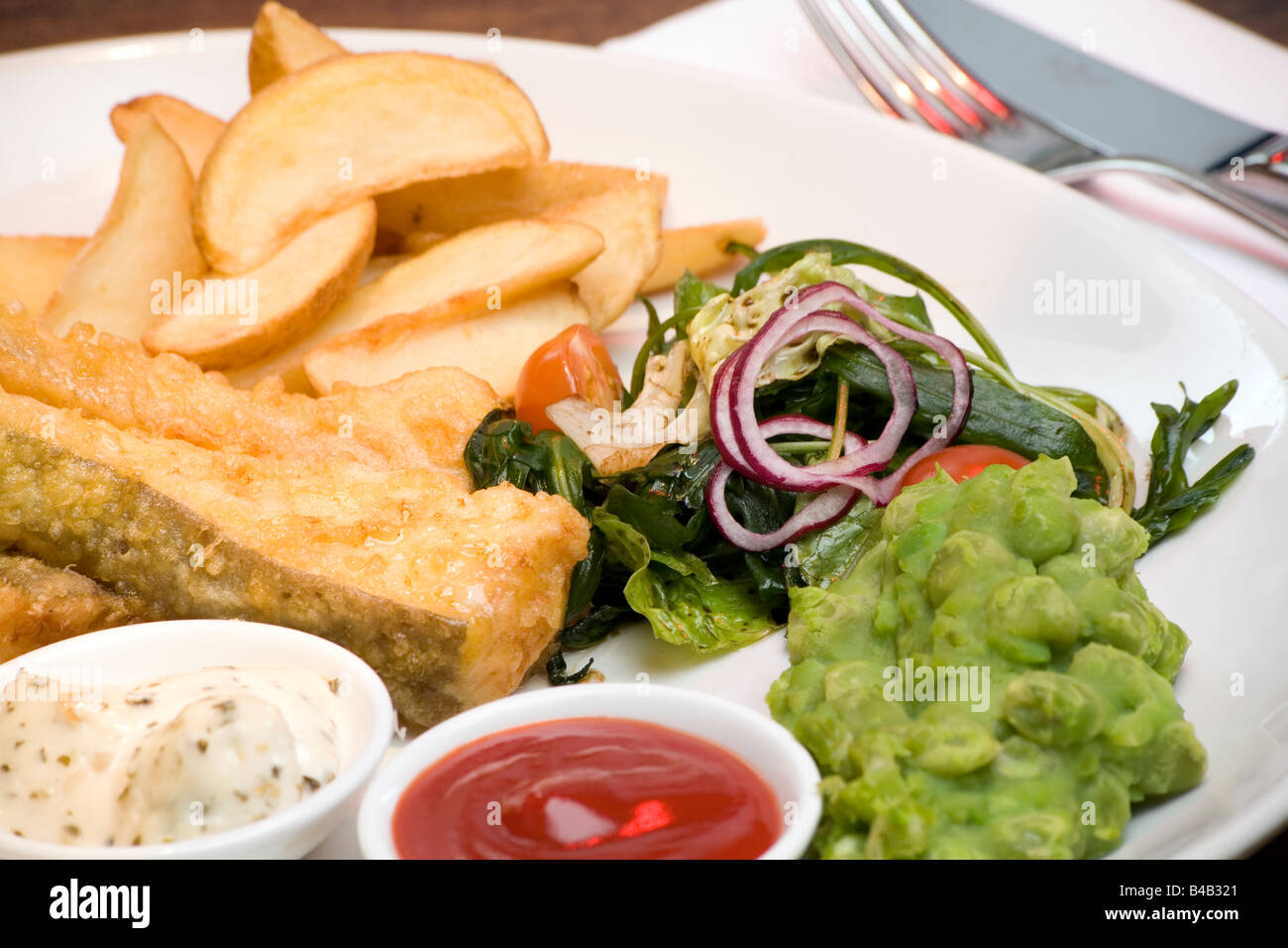 Lightly battered Cod with potato wedges dips and Mushy Peas Stock Photo ...