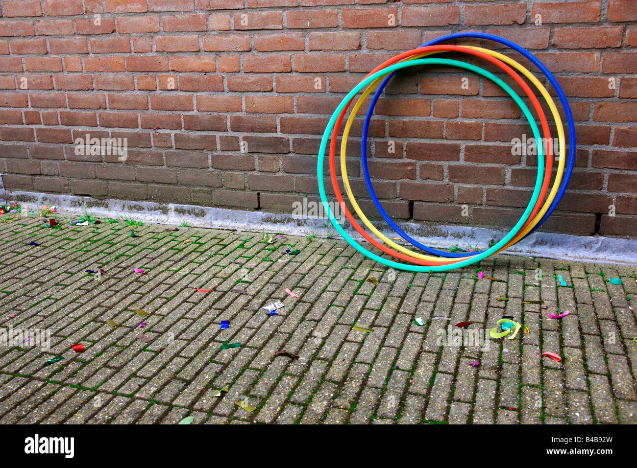 Colourful hula hoop rings on pavement by red brick wall Stock Photo - Alamy