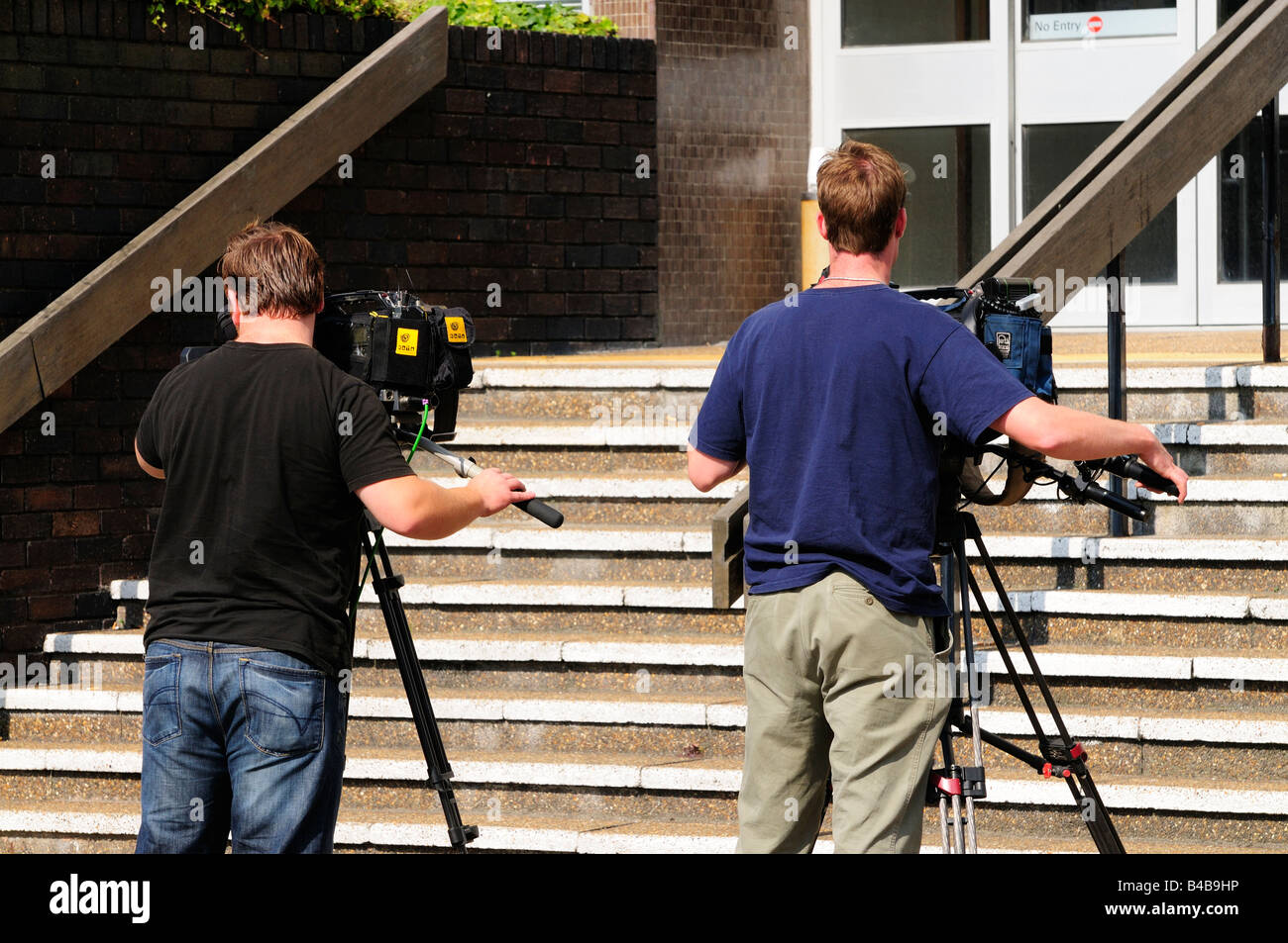 Rear view two film camera men working Street scene Stock Photo - Alamy