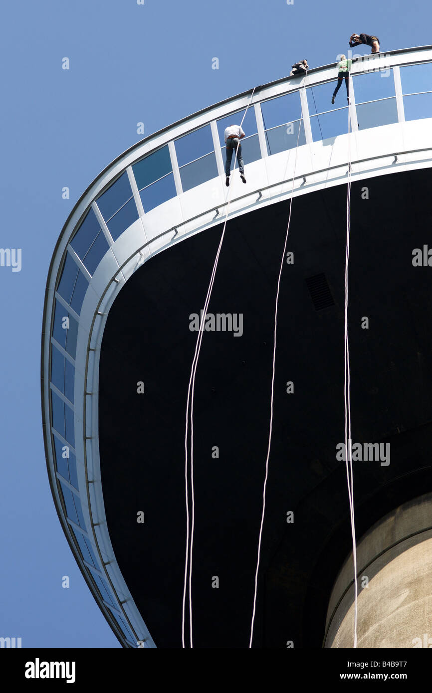 Three men people hanging climbing rope line concrete tower Euromast ...