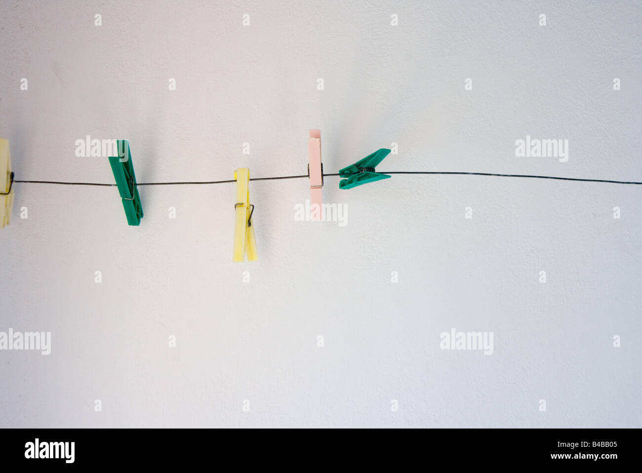 Clothes pegs on a washing line against a white wall Stock Photo - Alamy
