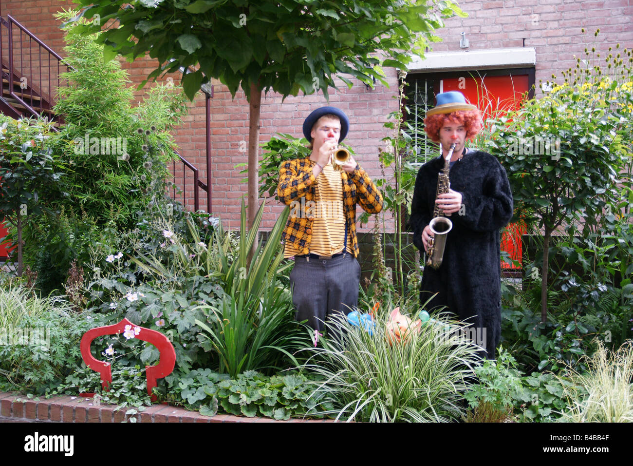 Artist clown buffoon two men dressed in circus dress playing trumpets ...