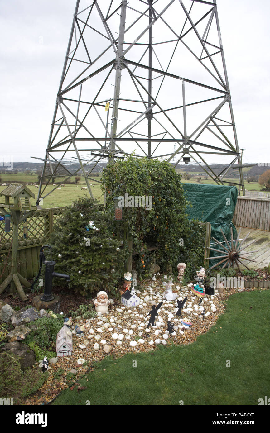 Gnomes and garden figures displayed below an electricity pylon in a ...