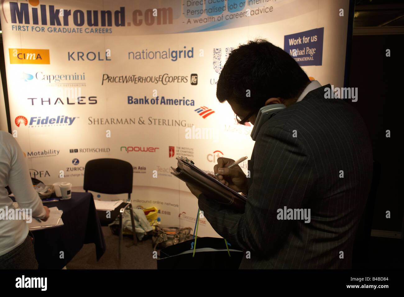 Taking notes on a stand at a graduate expo fair where company job ...