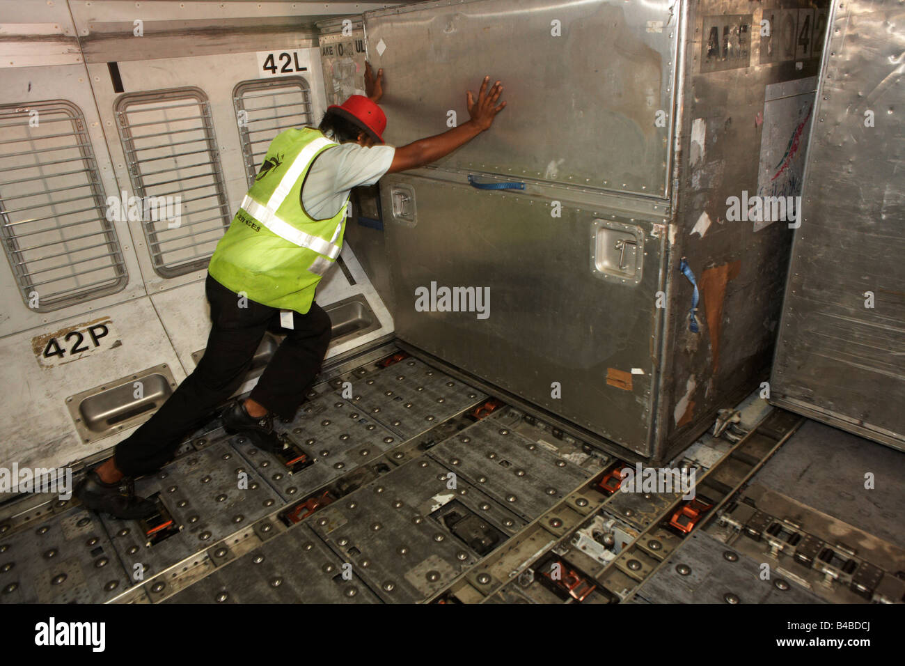 Beneath economy class flooring, a cargo handler manhandles a freight ...