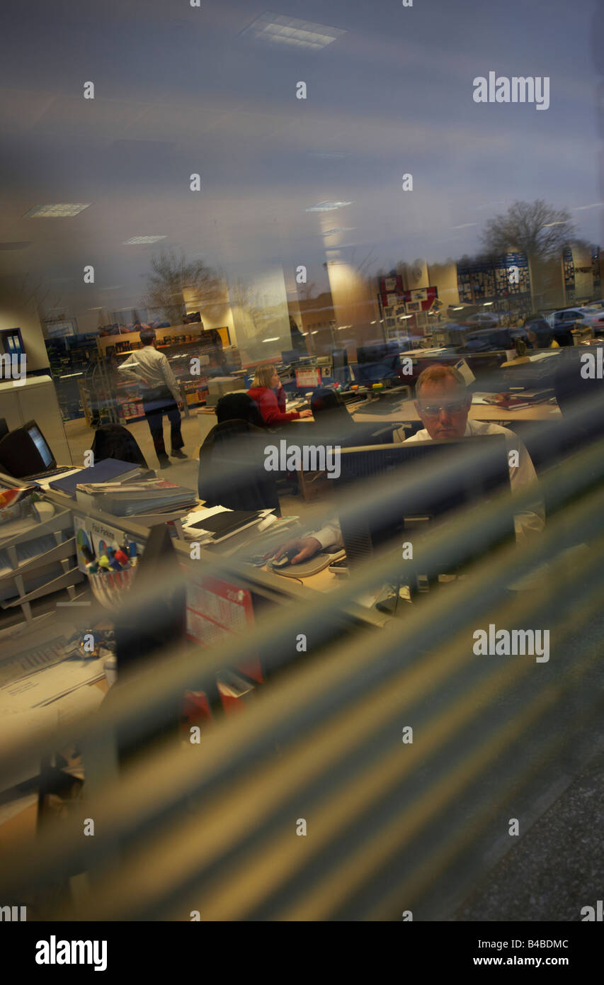 Seen through a window as daylight fades an employee works late at the ...