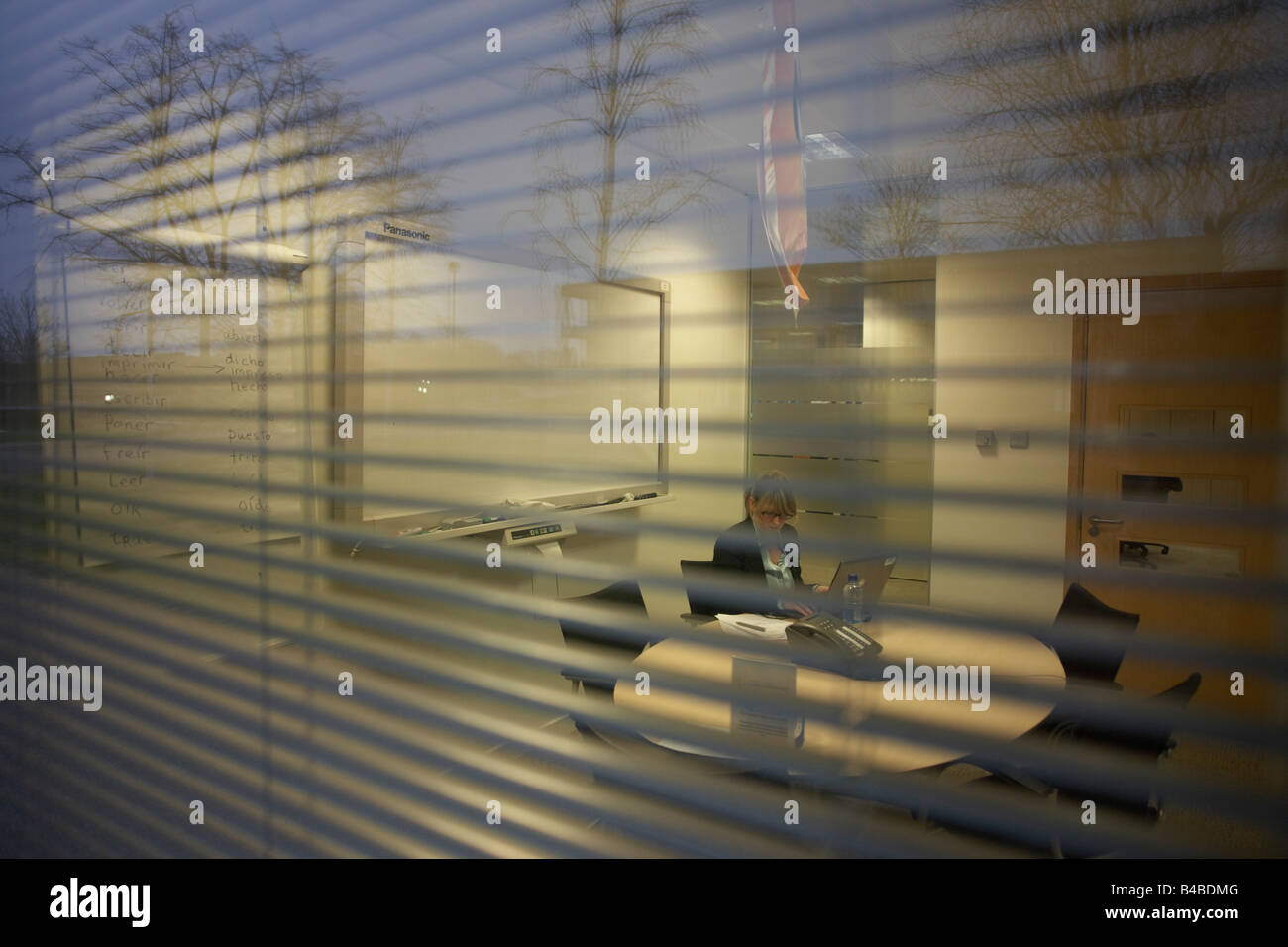 Seen through a window as daylight fades, an employee works late at the ...