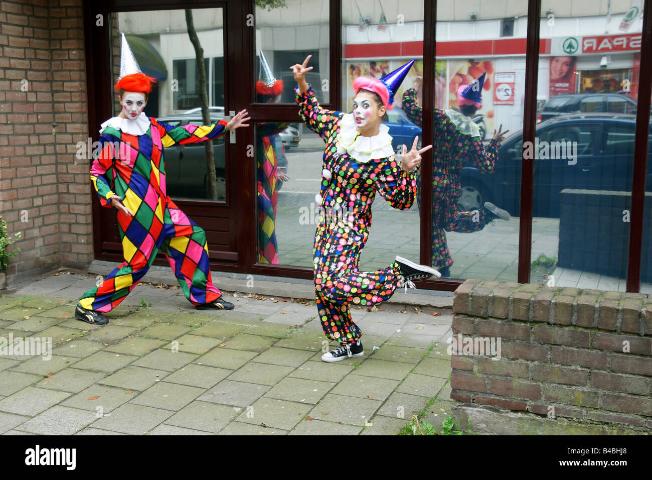 Two buffoons clowns circus women dancing outdoors in front of glass ...