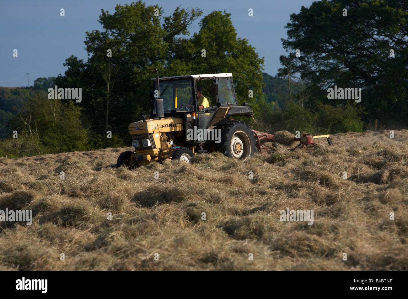 Tractor turning Hay UK Stock Photo - Alamy