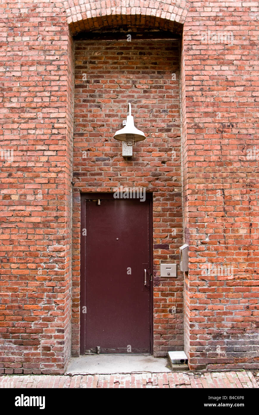 A simple steel door and light inset into a brick wall in downtown ...