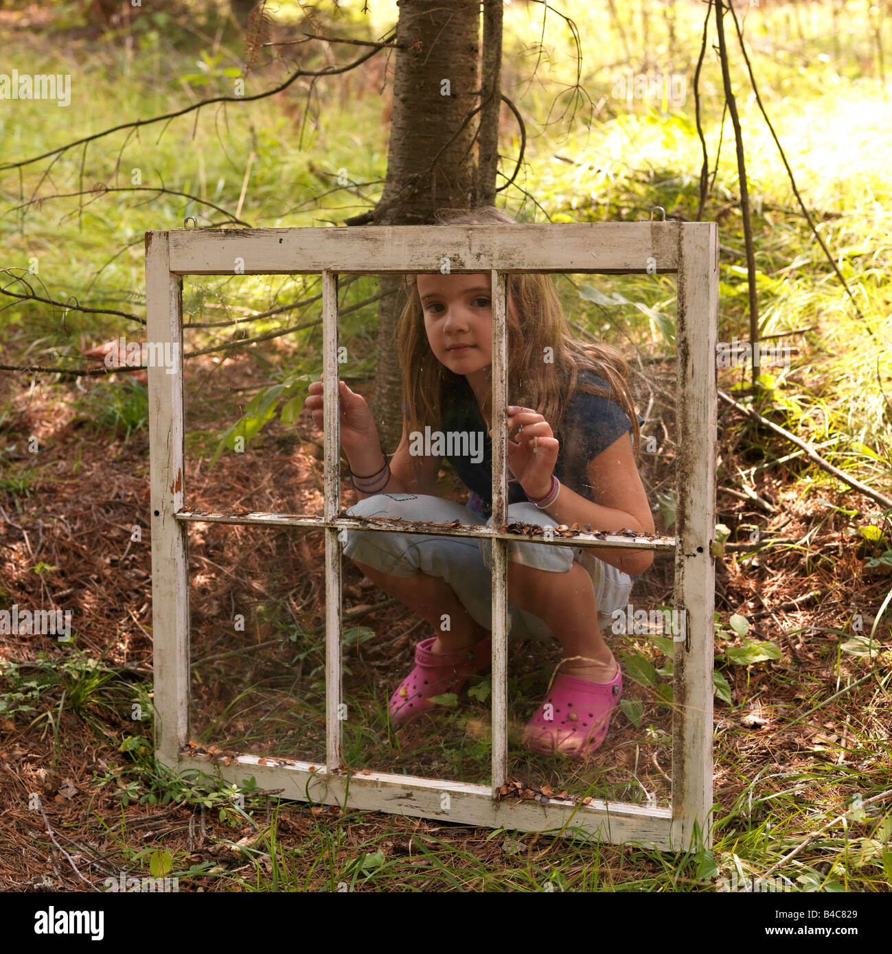 Young girl in woods, looking through old window Stock Photo - Alamy
