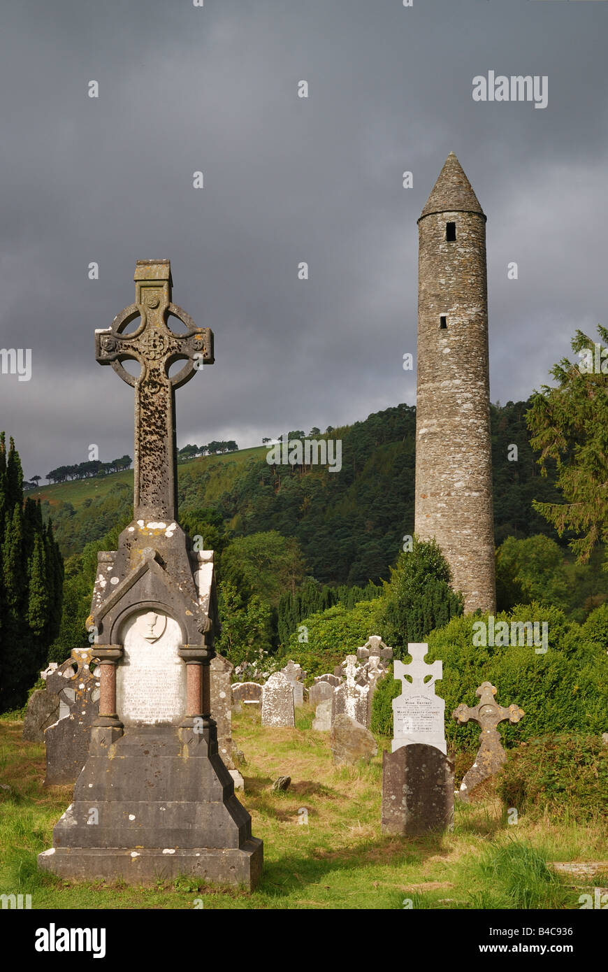Celtic cross with monastic tower in background at sunrise Glendalough ...