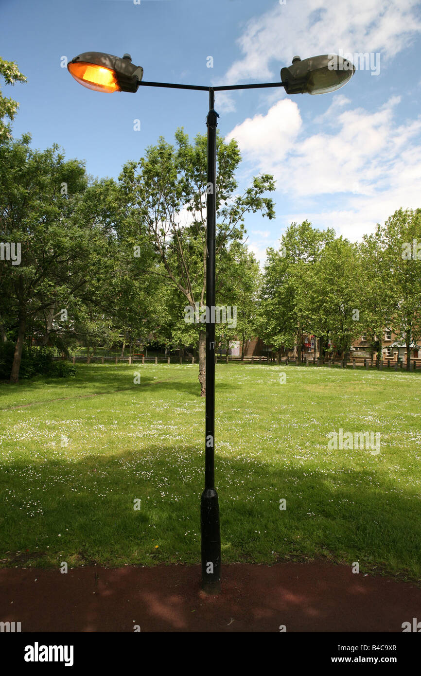 Street lamp left on during the day against a blue sky with clouds and ...