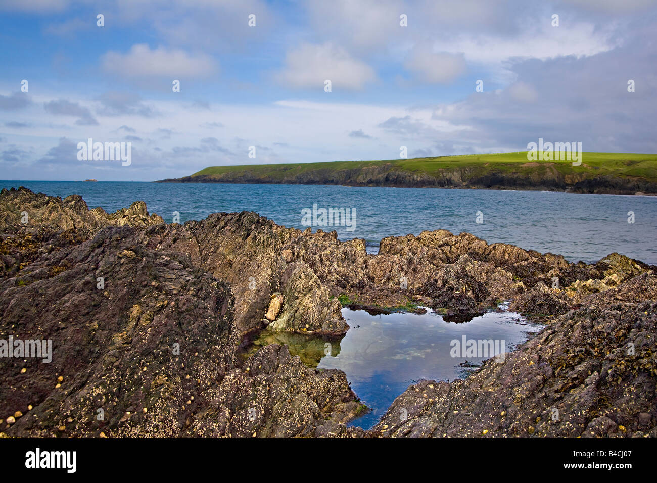 A rock pool with the sea and cliffs behind Stock Photo - Alamy