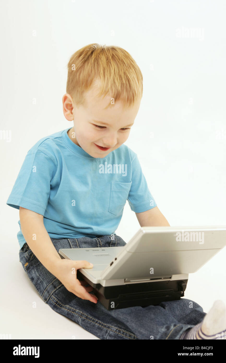 Two year old boy sitting down watching a DVD on his portable DVD player ...