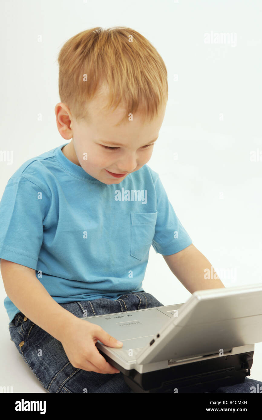 Two year old boy sitting down watching a DVD on his portable DVD player ...