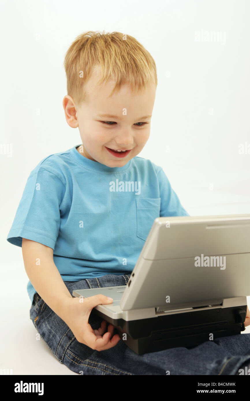 Two year old boy sitting down watching a DVD on his portable DVD player ...
