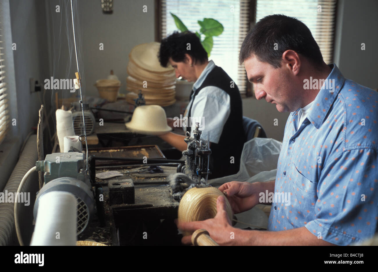 A hat maker and assistent working a home factory in the village of ...
