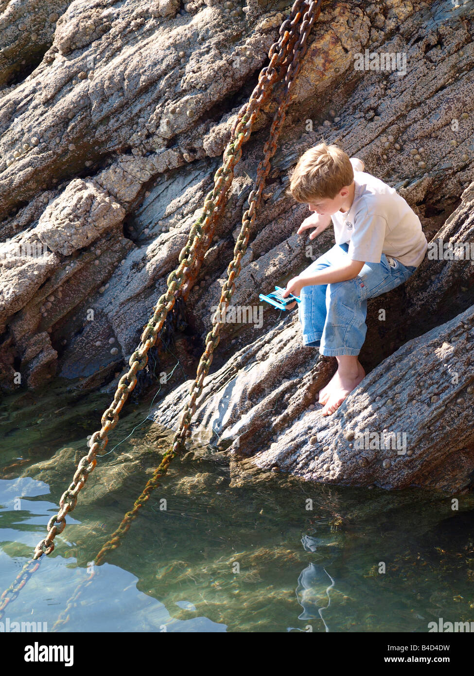 Young boy fishing of rocks for crabs Stock Photo - Alamy