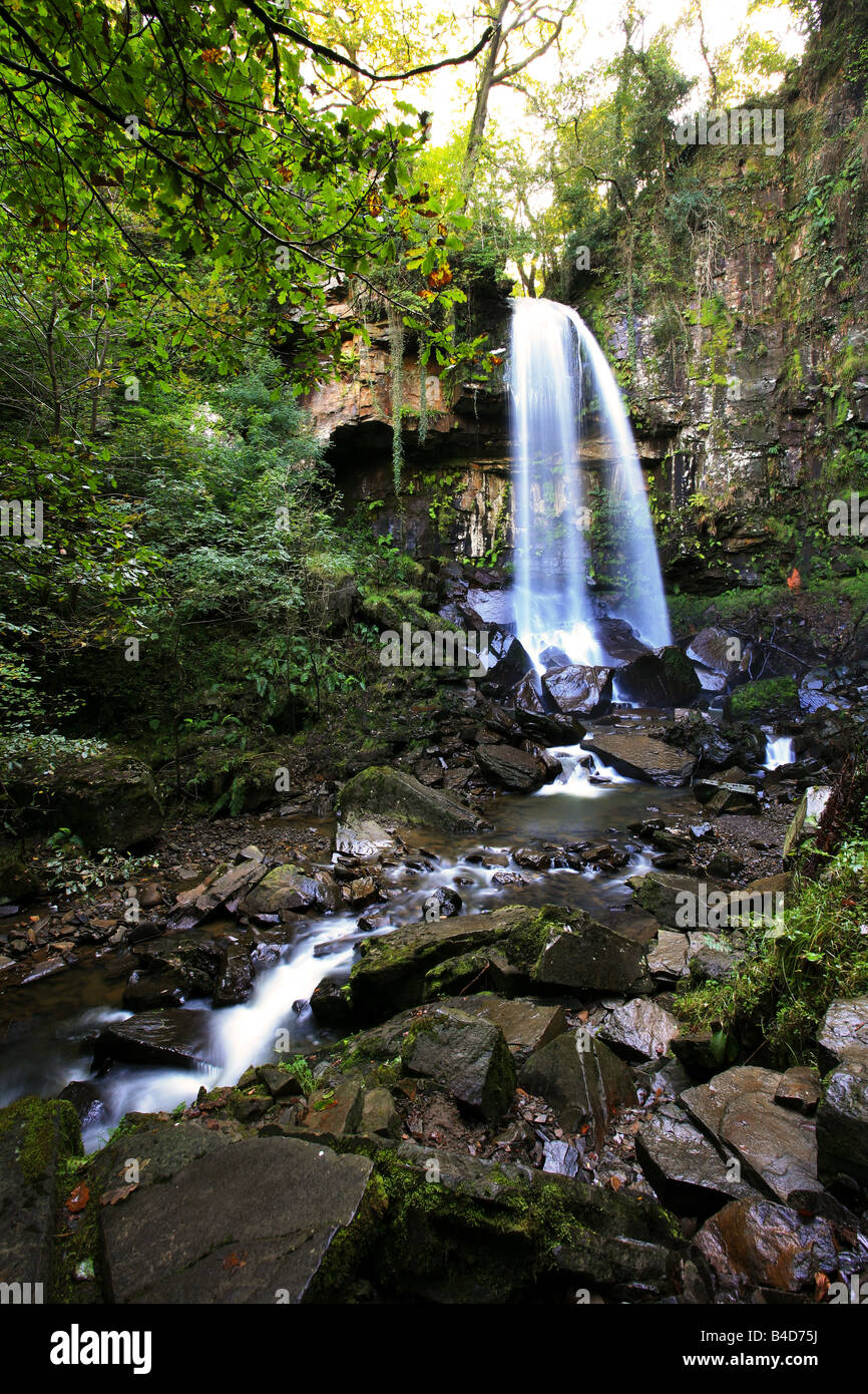 Single waterfall flows falls onto over river bed rocks surrounded by ...