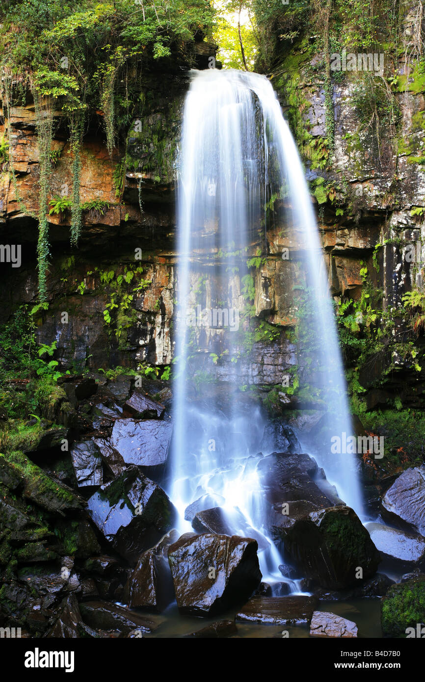 Closeup single waterfall flows falls onto over river bed rocks ...