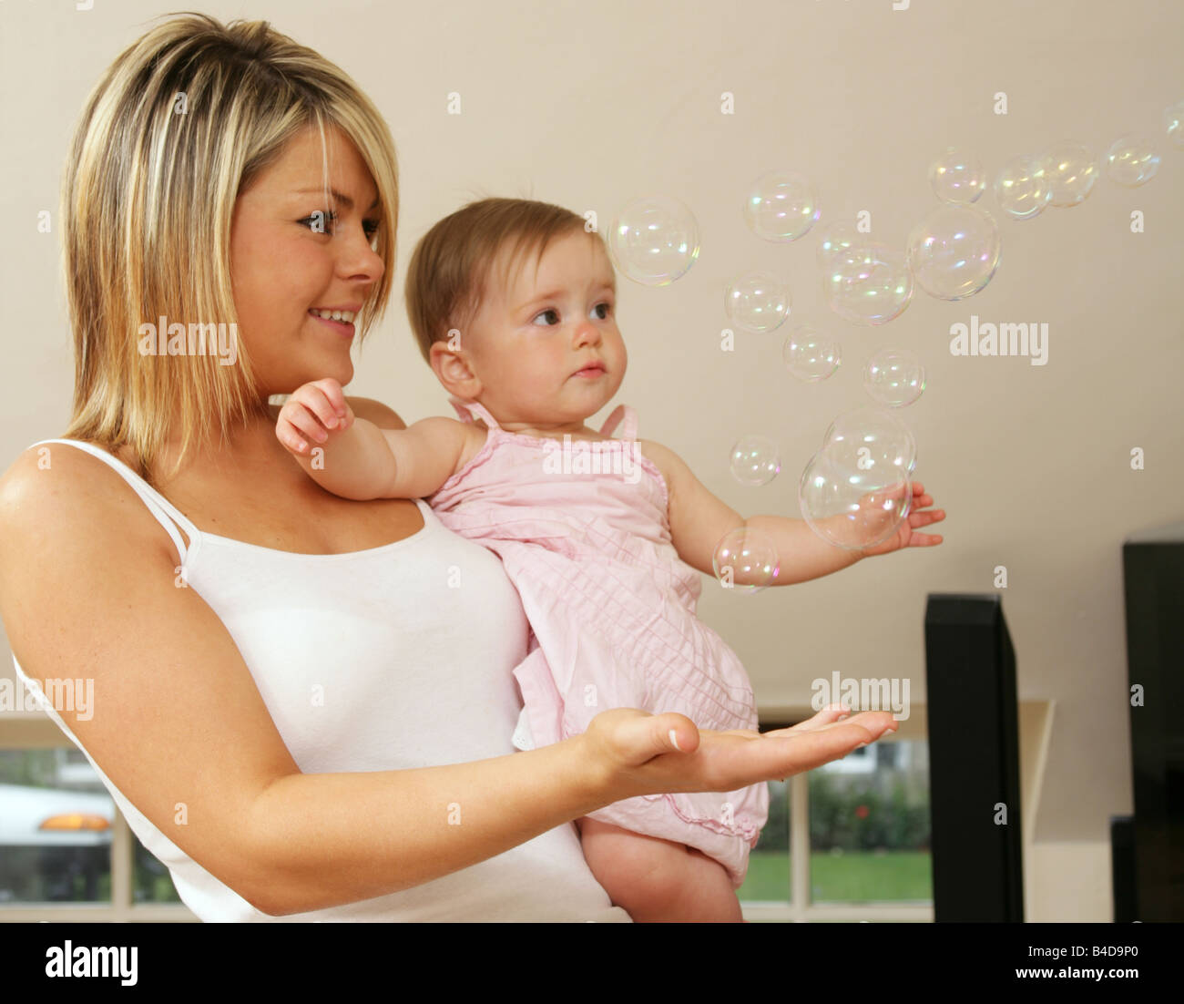 Mother and baby daughter holding hands out catching soap bubbles Stock ...