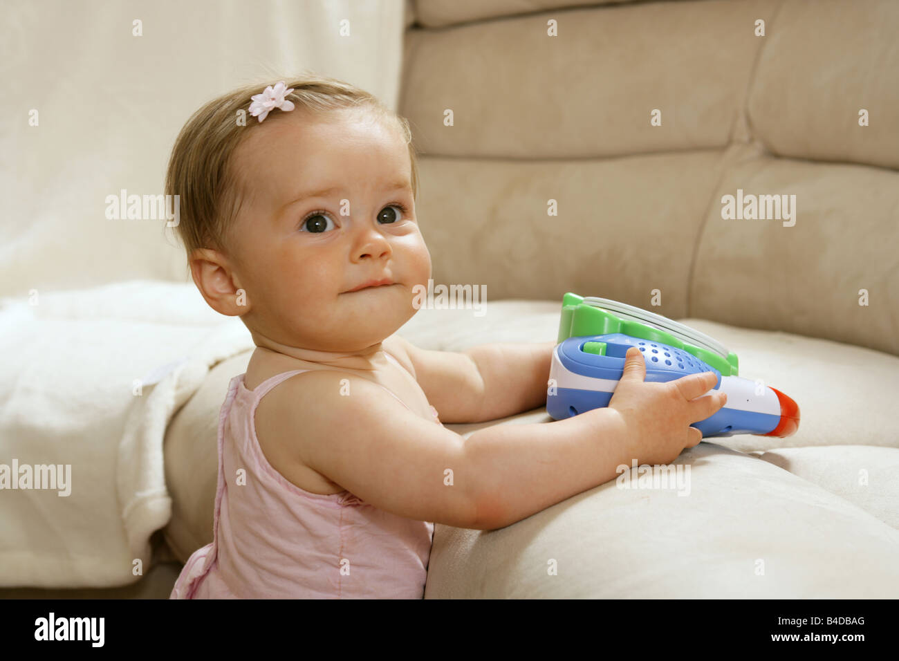 nine month old girl holding onto a plastic toy Stock Photo - Alamy