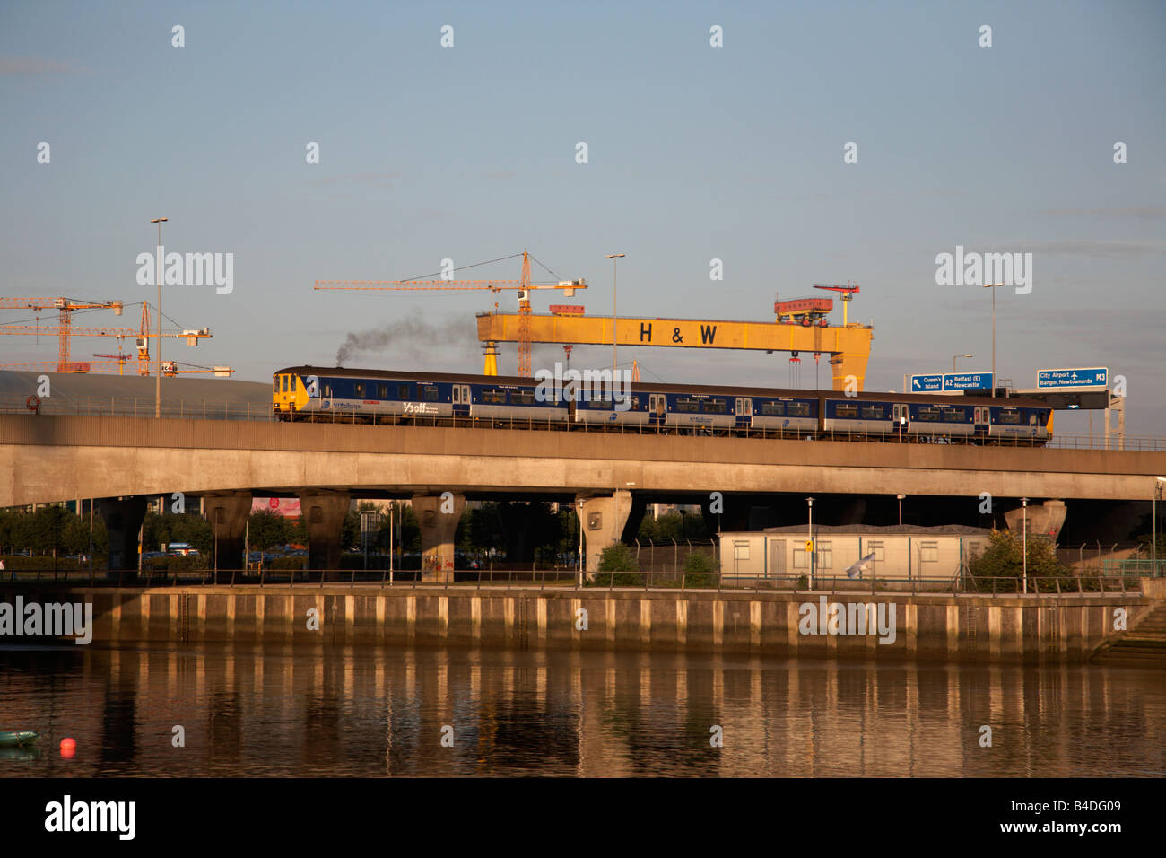 train crossing the River Lagan bridge with cranes in the background ...