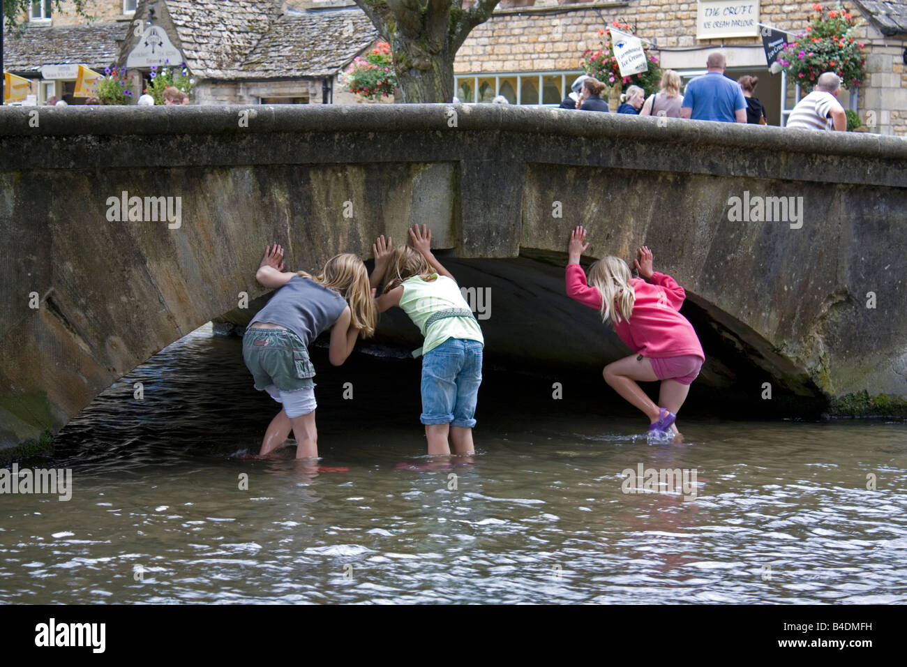 Children grils playing under bridge in stream Bourton on the Water UK ...