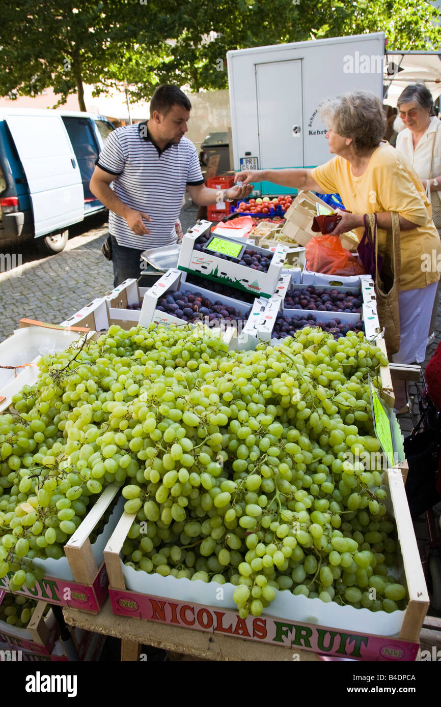 Woman paying for fruit on market stall selling grapes Neubrandenburg ...