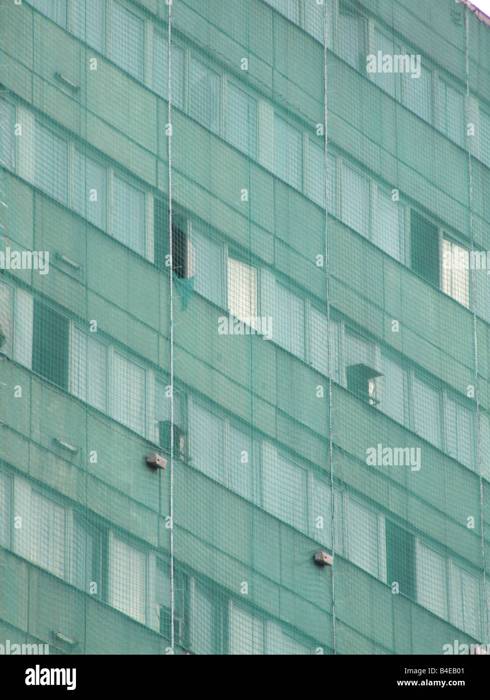 high rise building with green protective mesh net Stock Photo - Alamy