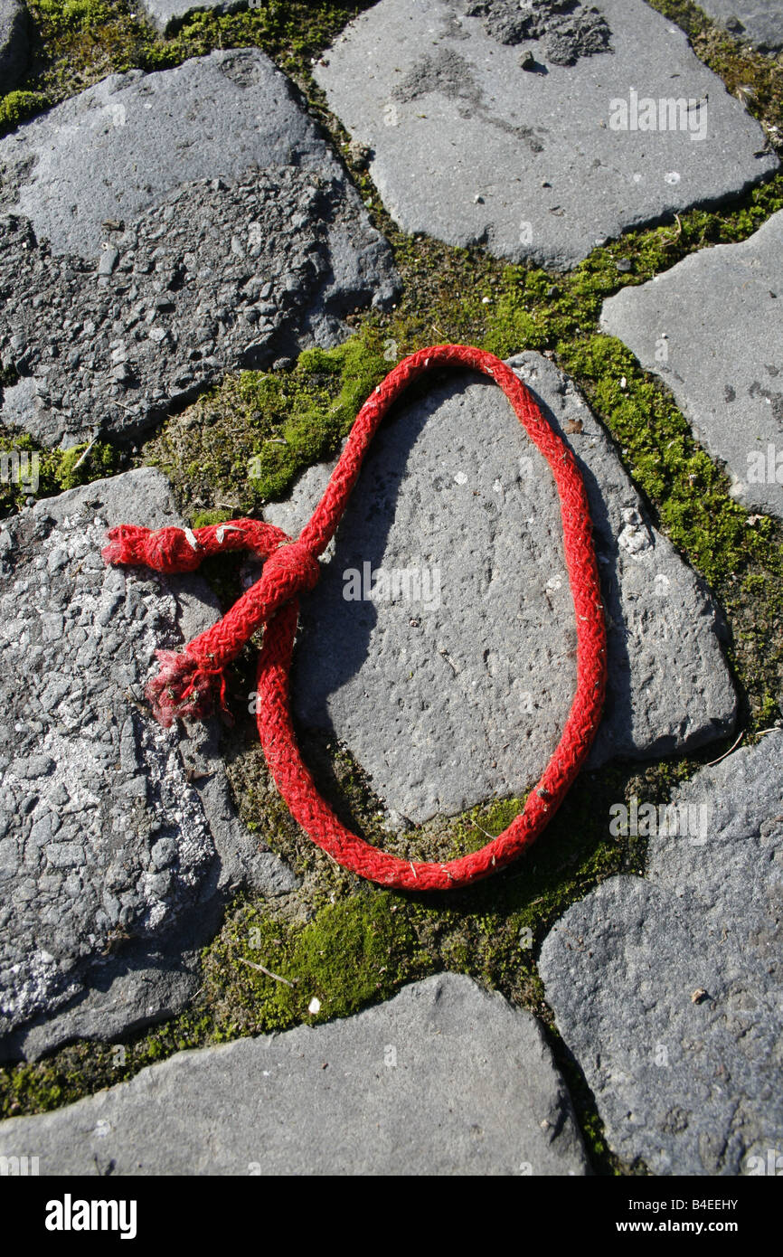 one piece of red string on cobbles pavement outdoors Stock Photo - Alamy