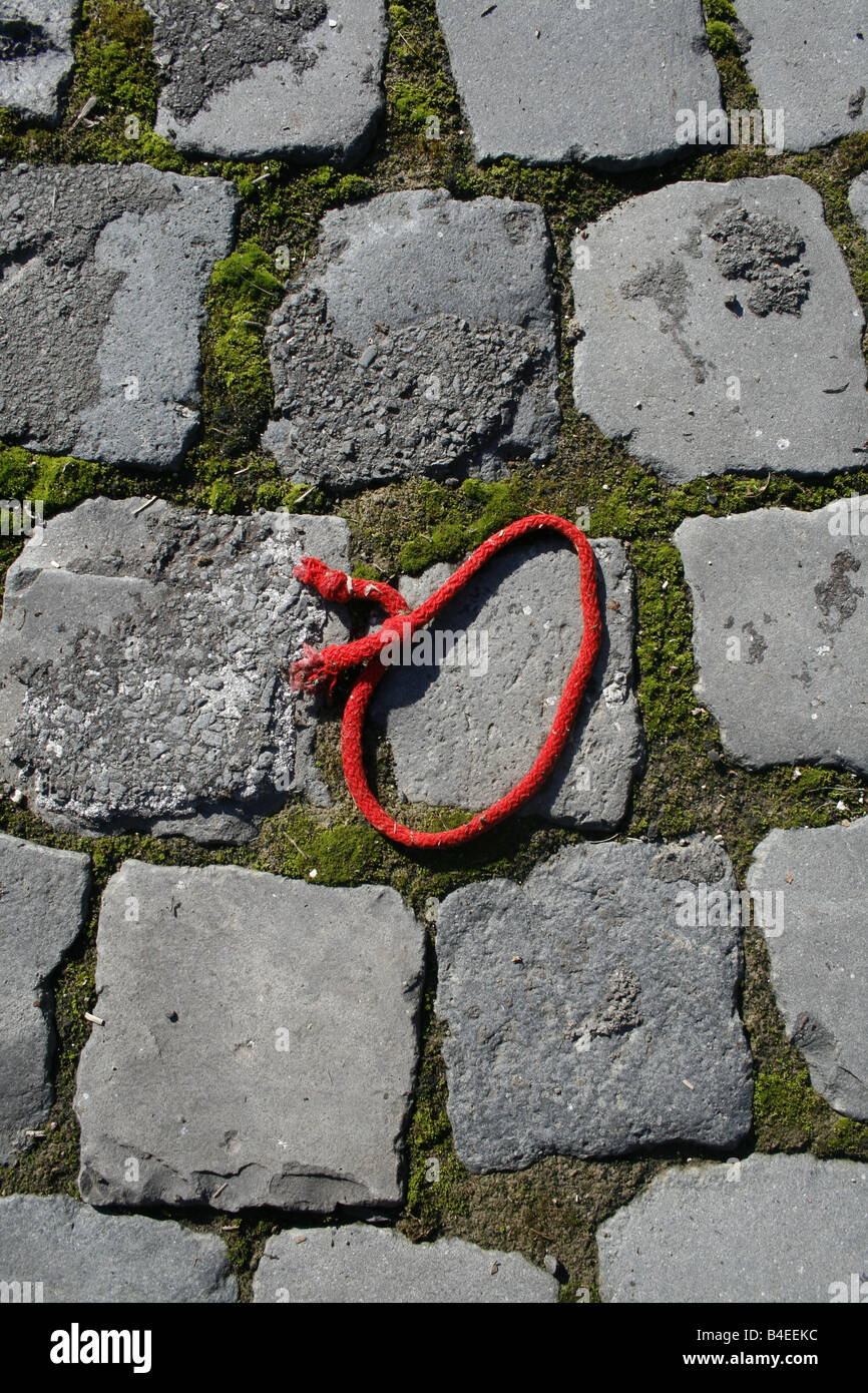 one piece of red string on cobbles pavement outdoors Stock Photo - Alamy