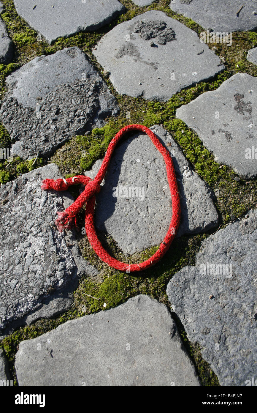 one piece of red string on cobbles pavement outdoors Stock Photo - Alamy