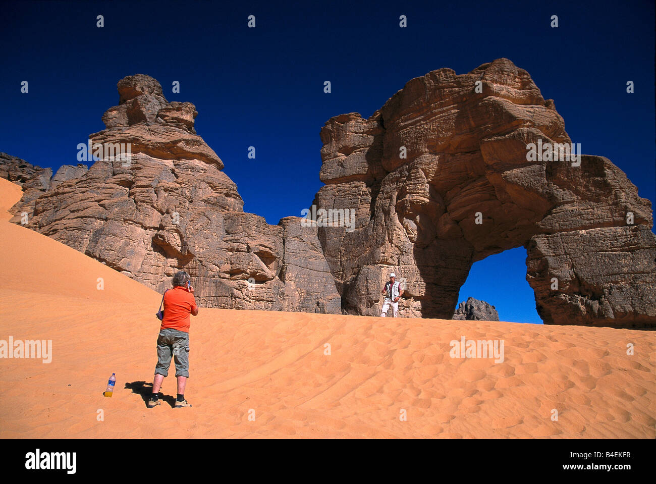 Tourists taking pictures near a rocky arch at Jebel Acacus, Sahara ...