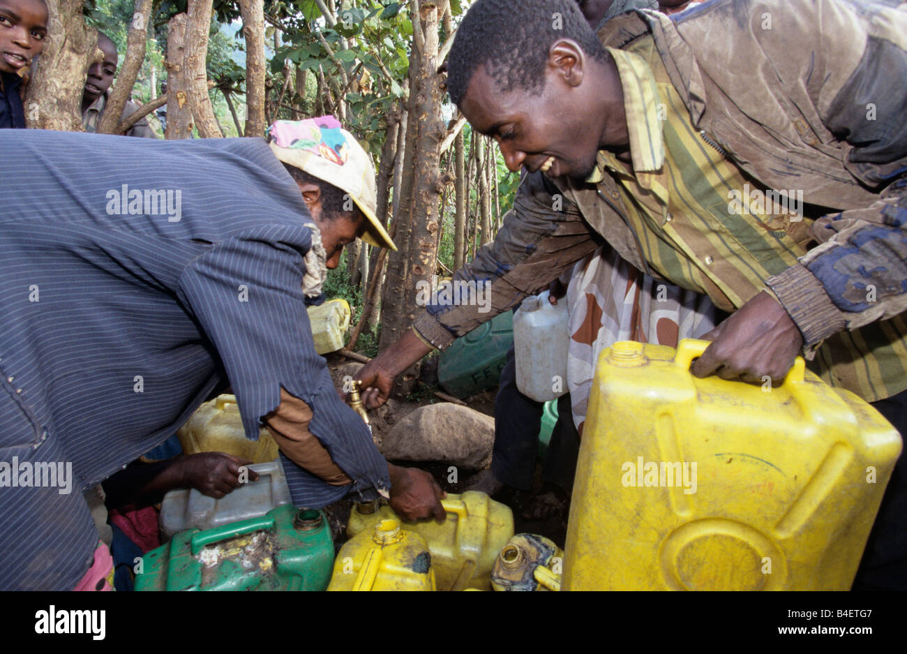 Men collecting water at village tap, Uganda Stock Photo - Alamy