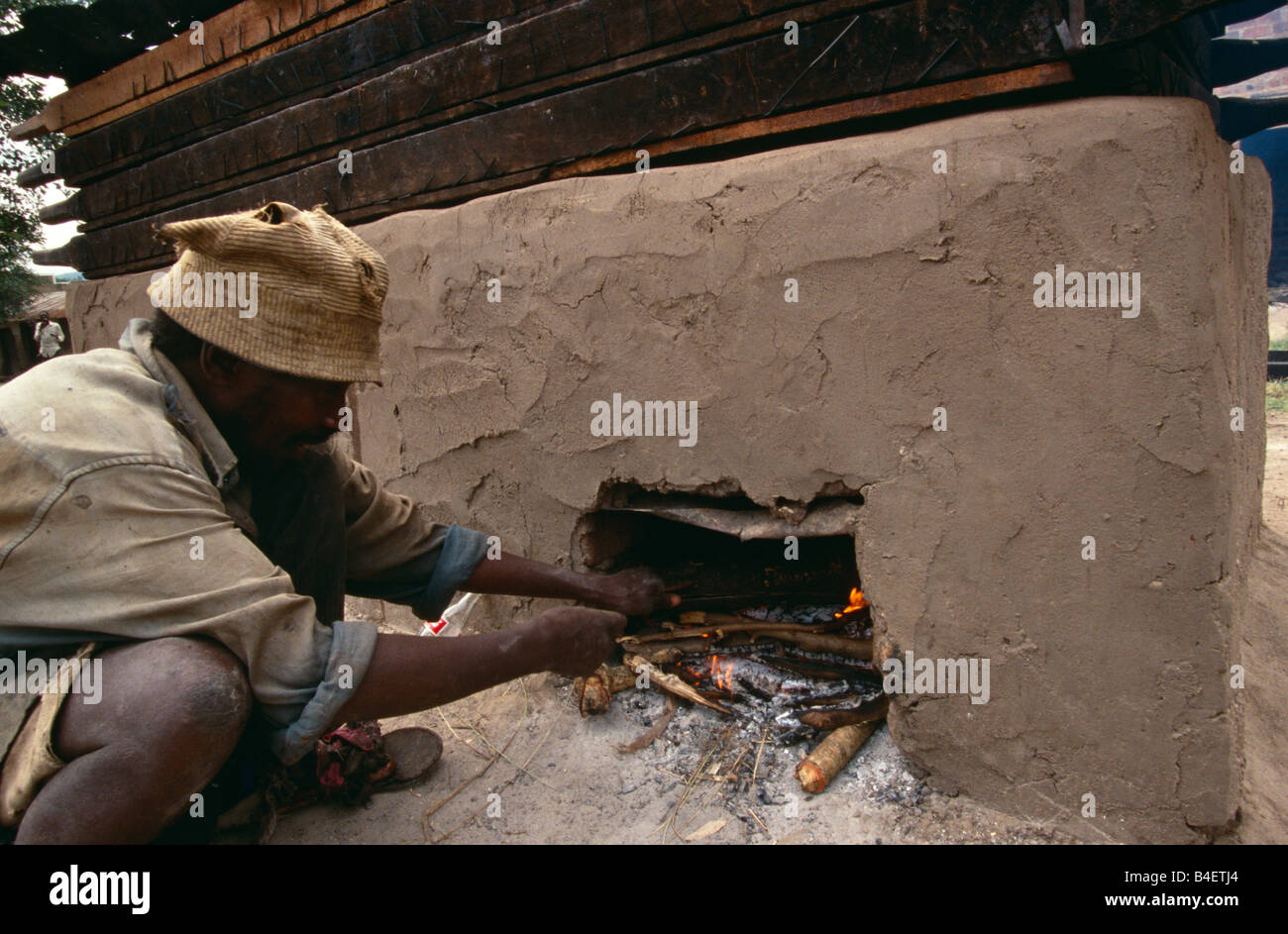 Man working on getting traditional clay oven fire burning. Uganda Stock ...
