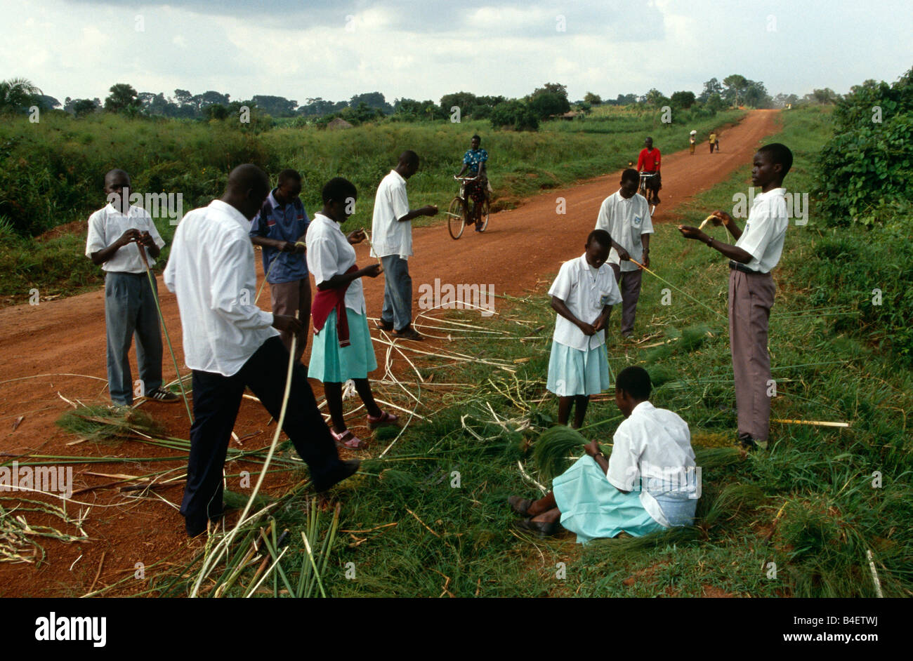 Villagers and schoolchildren learning o weave by roadside. Uganda Stock ...