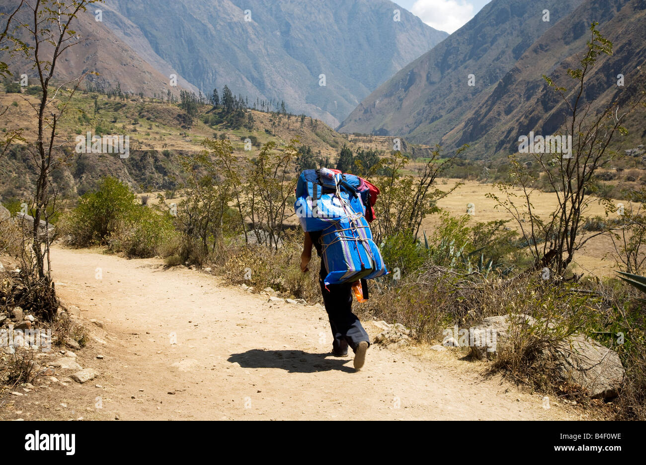 A porter carrying a heavy load along the Inca Trail or Camino Inka in ...