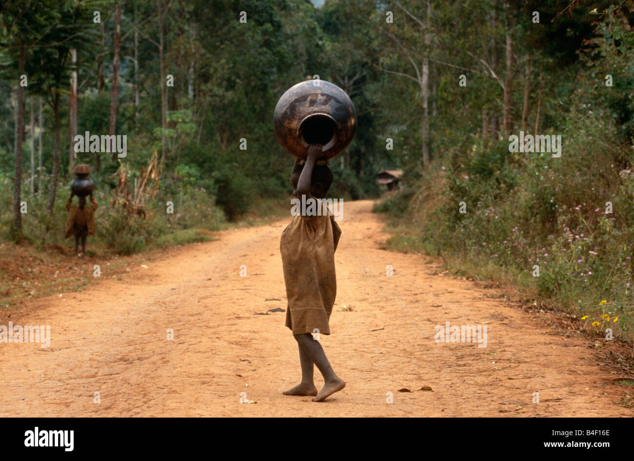 Girl carrying clay pot on head across dirt road, Burundi, Africa Stock ...