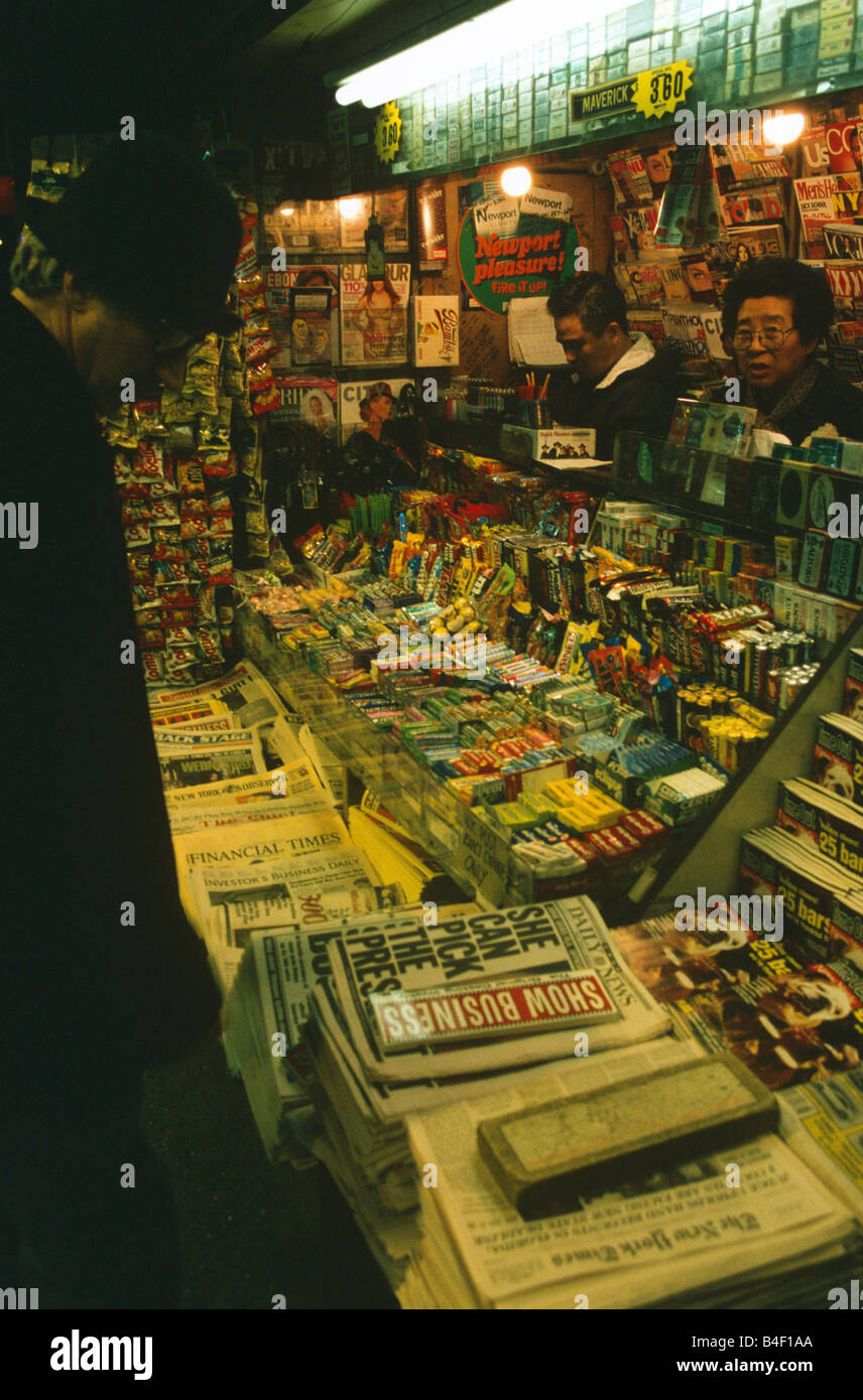 Man reading newspaper at newsstand of asian couple, Paris, France Stock ...