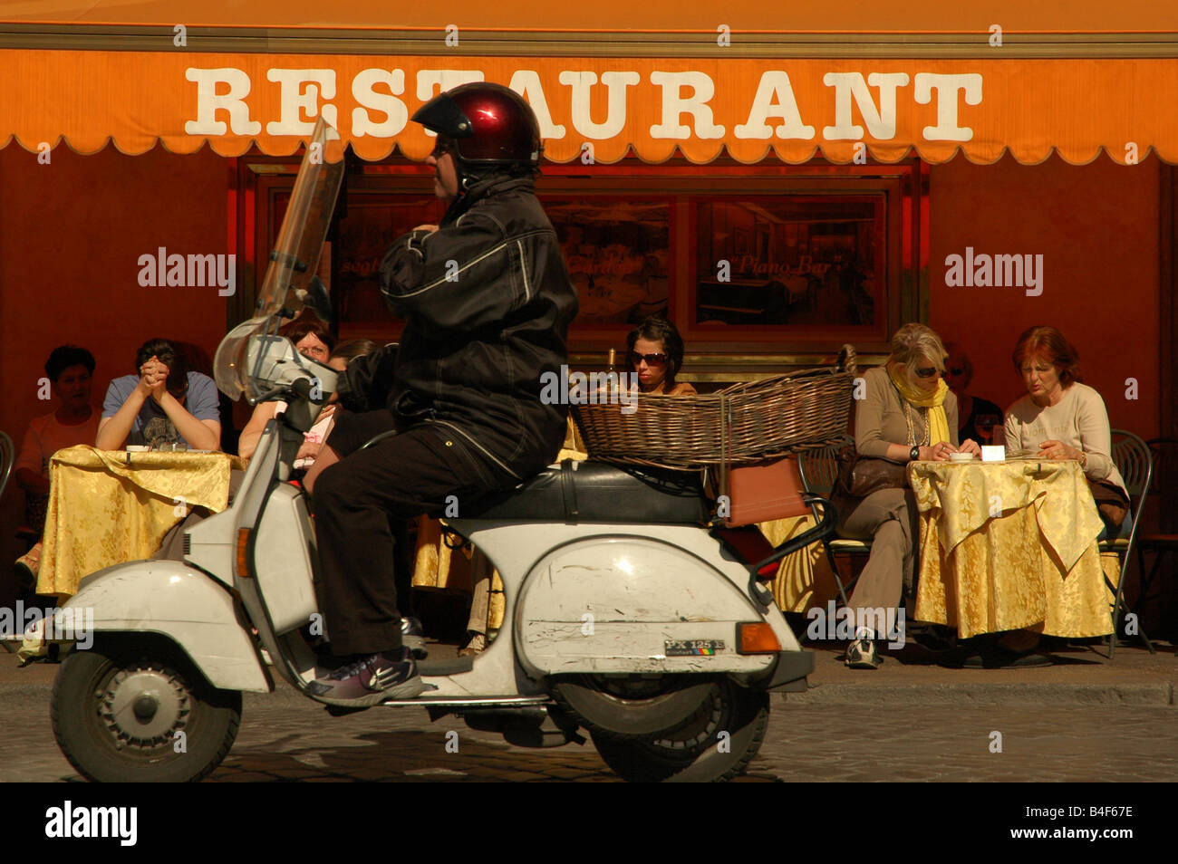 a scooter passing an italian restaurant Stock Photo - Alamy
