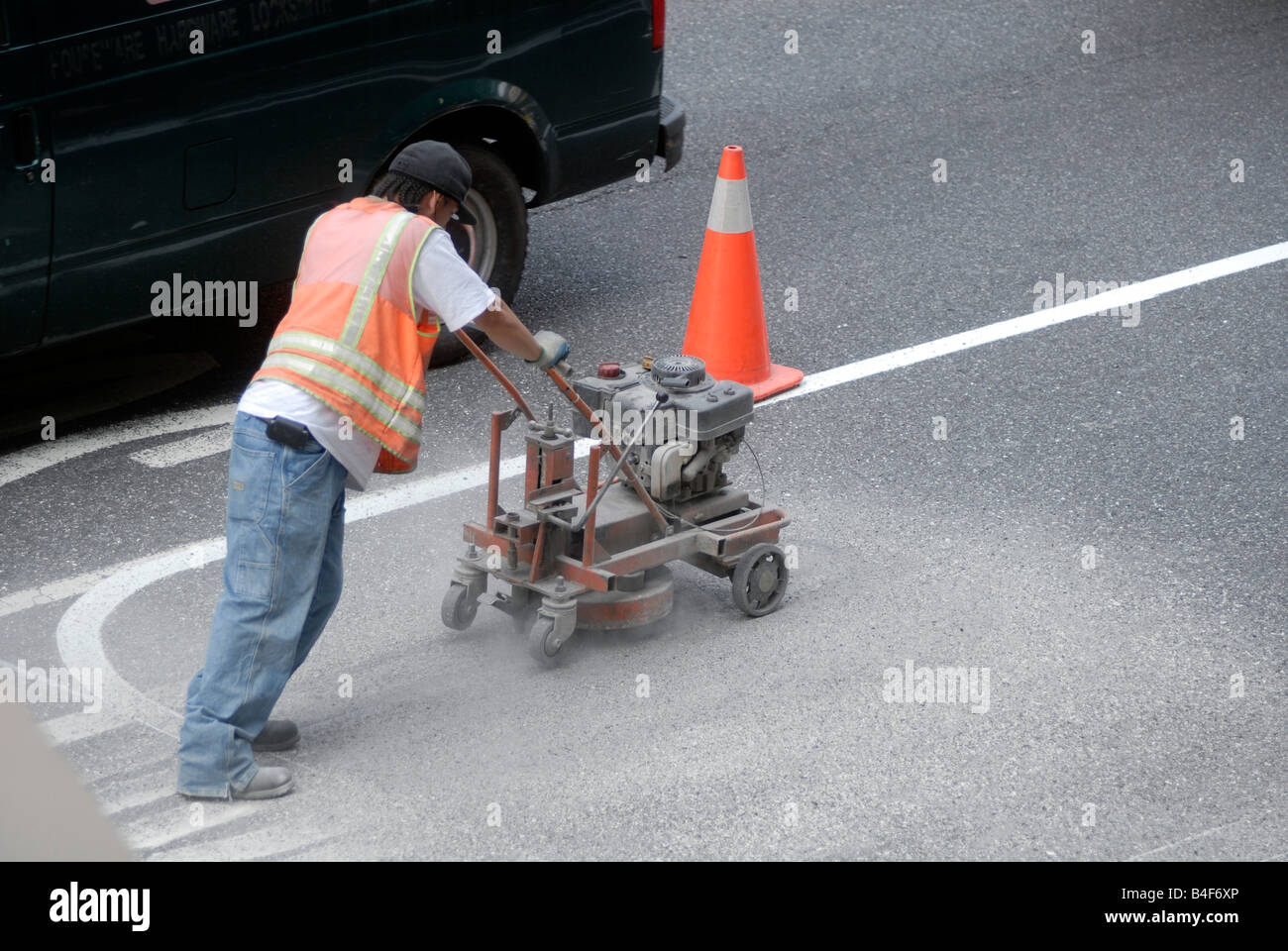 An employee of the NYC Department of Transportation grinds ...