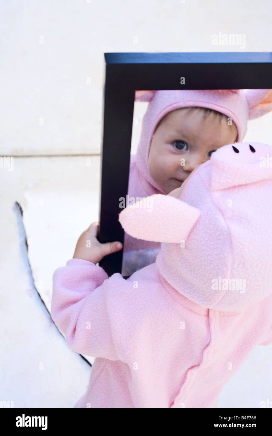 A toddler plays make believe with her mirror reflection in a pig ...