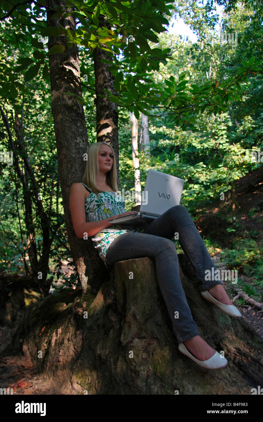 Girl with laptop sitting in a forest Stock Photo - Alamy