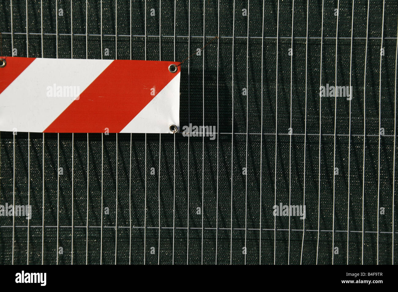 red white hazard warning sign notice on building site high metal fence ...