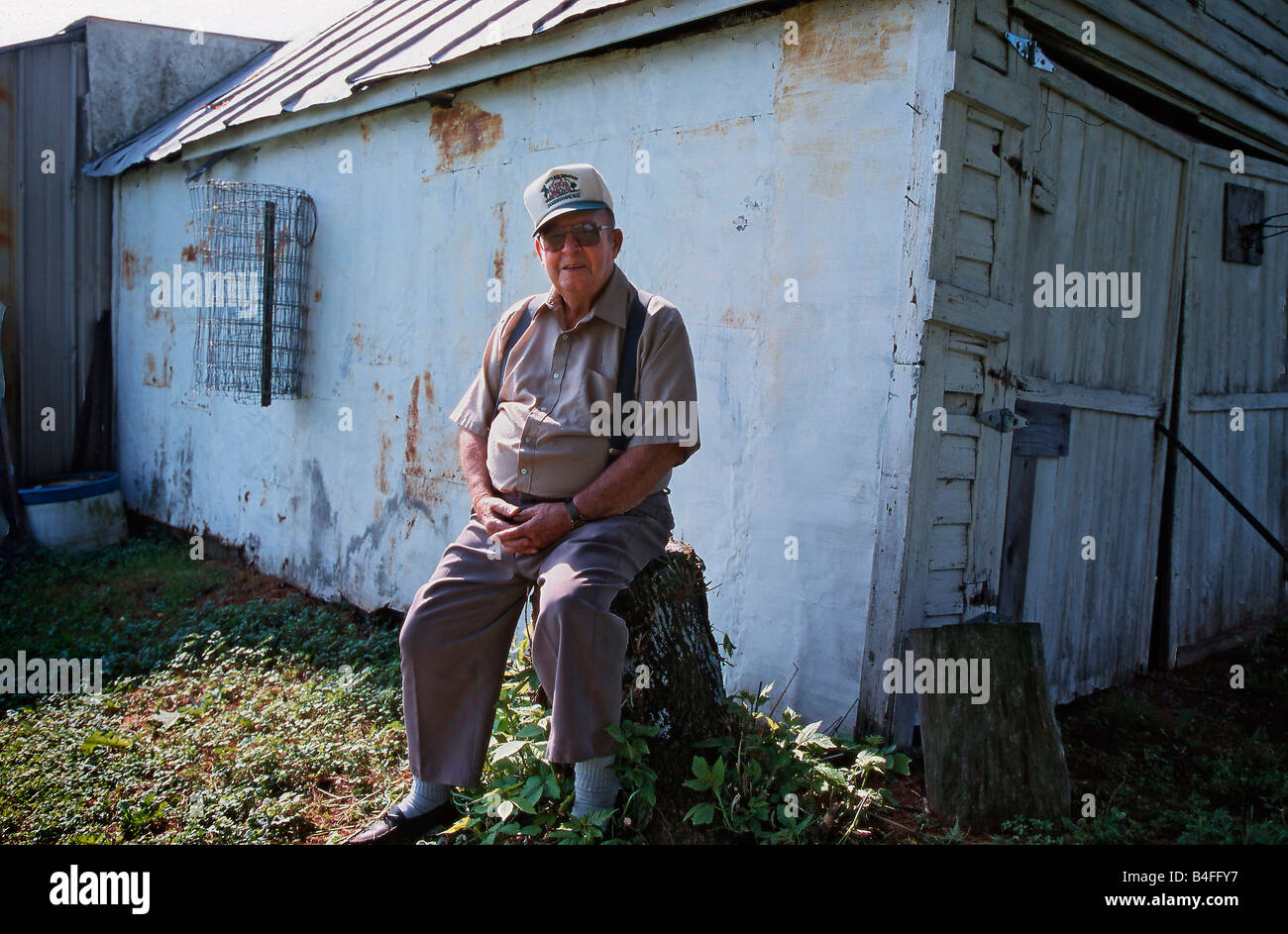 Older man sitting on a stump Stock Photo - Alamy