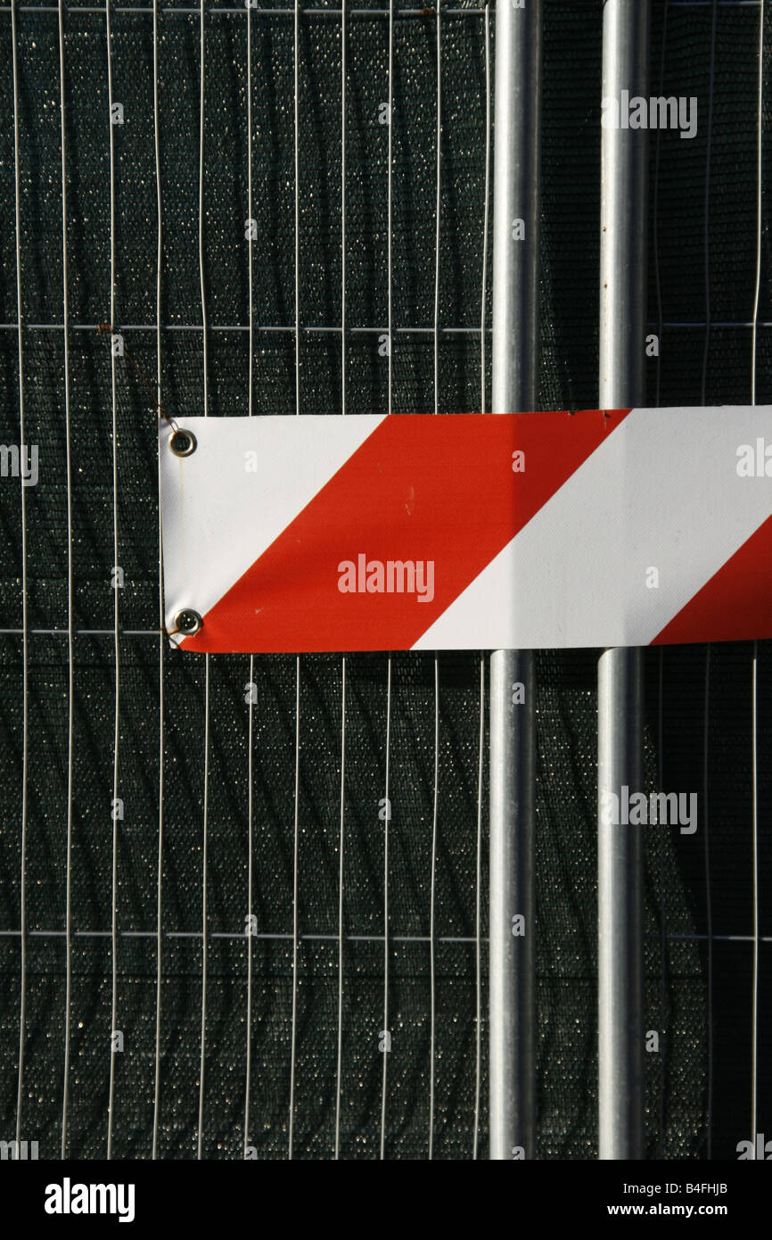red white hazard warning sign notice on building site high metal fence ...