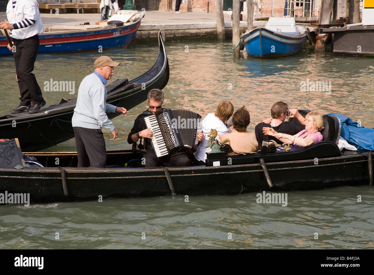 Tourists enjoying a gondola cruise with accordian accompaniment, Venice ...
