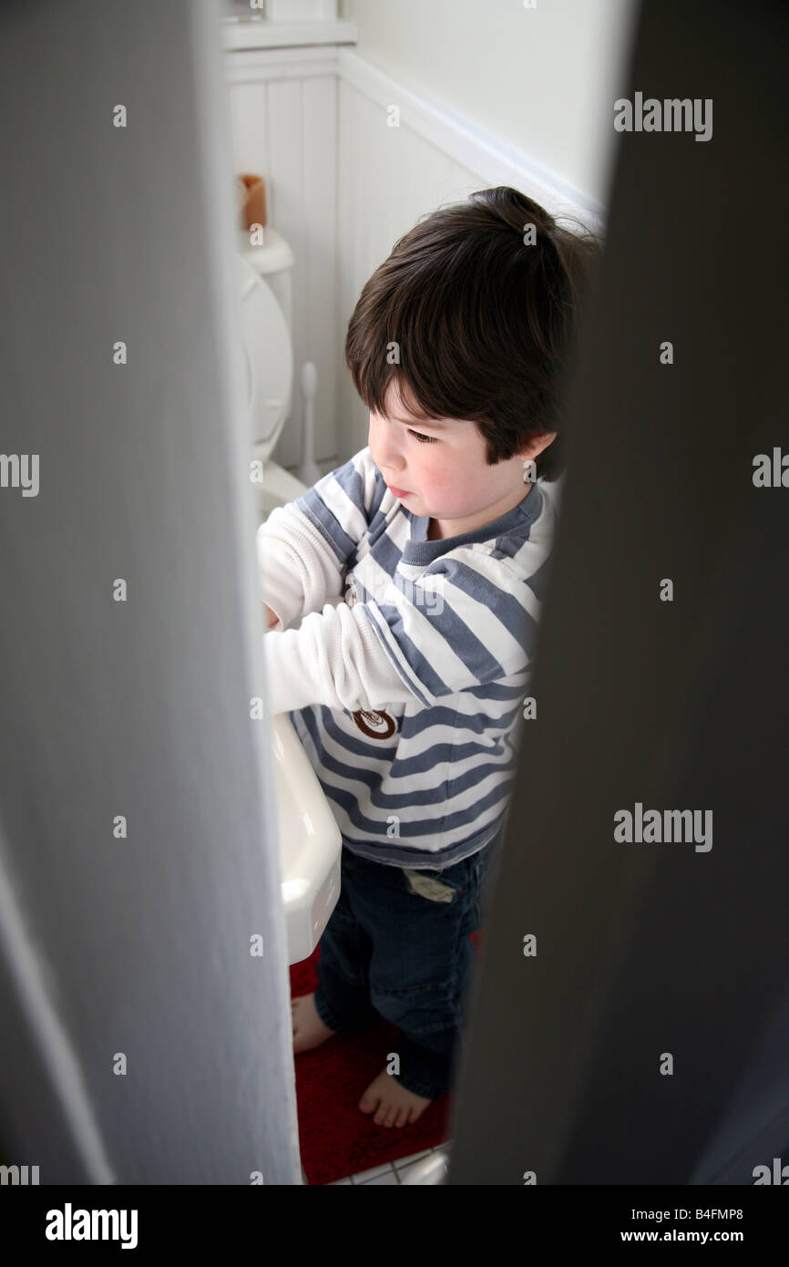 Boy washing hands, viewed through crack in bathroom door Stock Photo ...